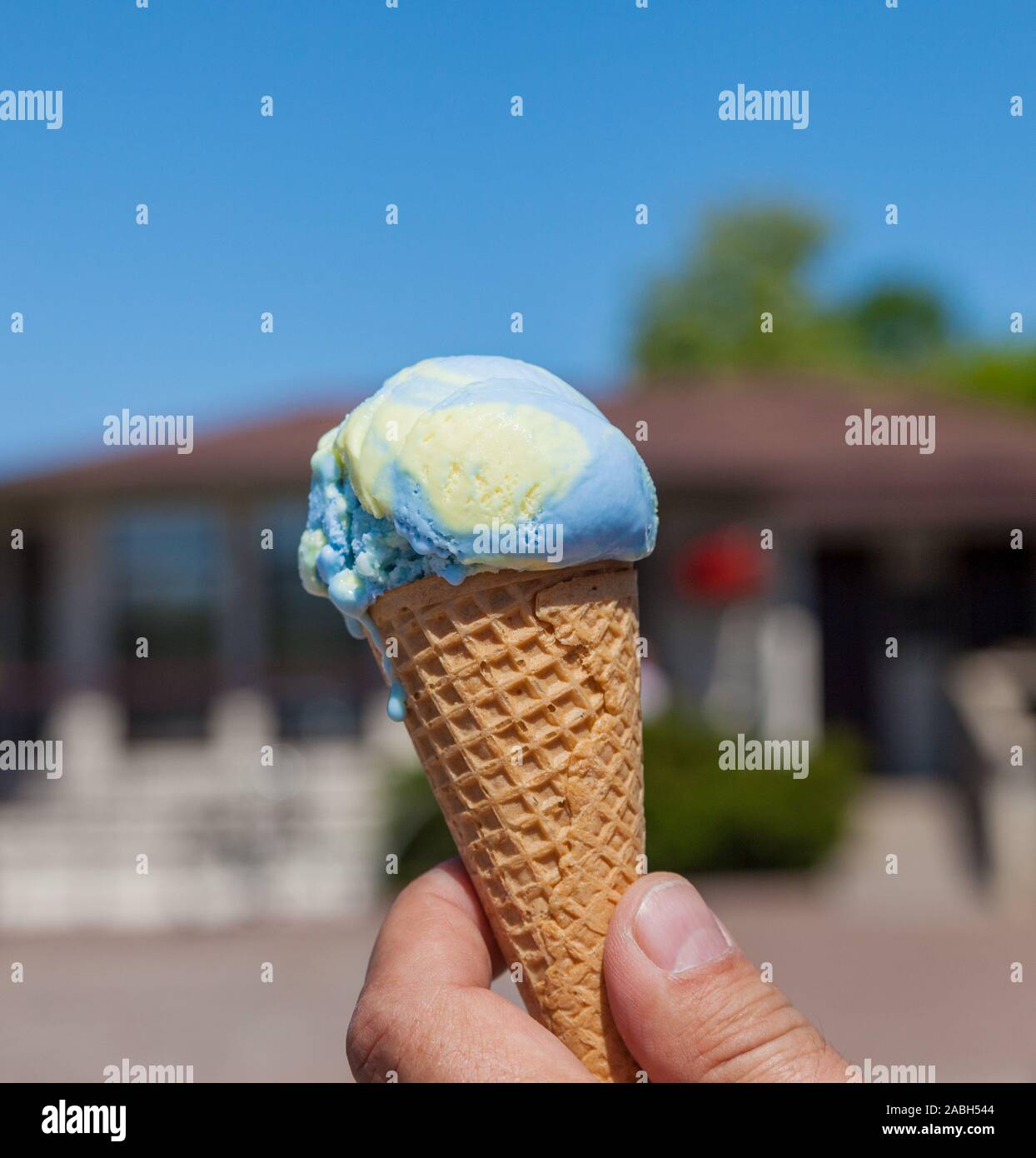 Male hand holding ice cream cone on building of cafe background Stock ...
