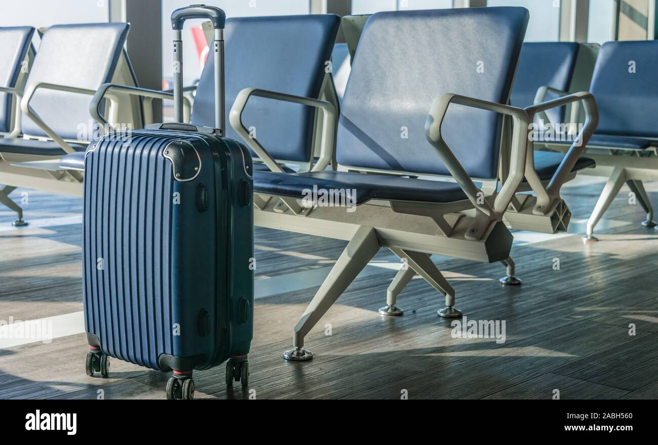 Small plastic travel suitcase in the airport hall Stock Photo - Alamy