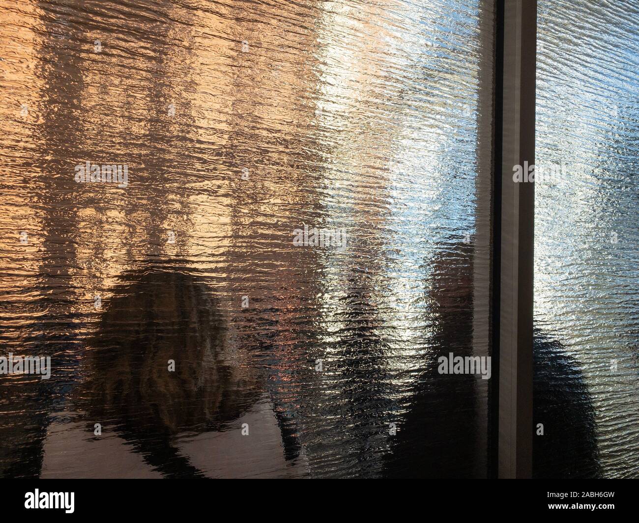 People standing waiting in a queue indoors viewed from behind blurred ...