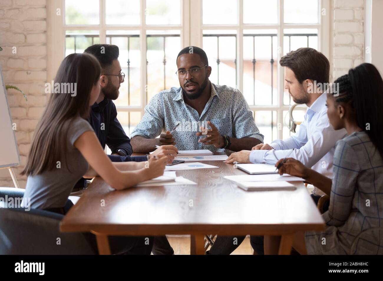 Diverse group of professionals listening to african american team ...