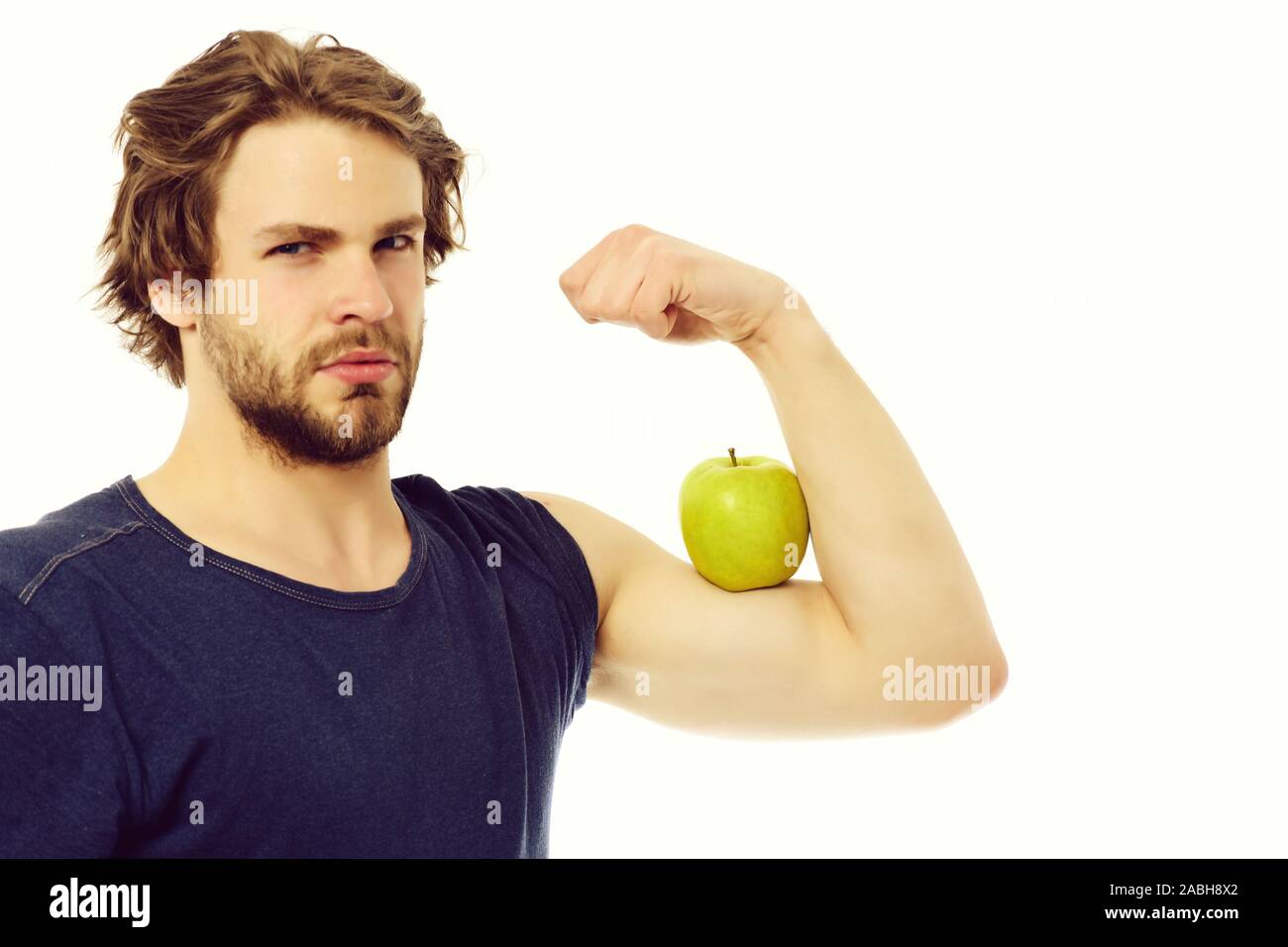 Caucasian guy with confident look holding green apple on his muscle ...
