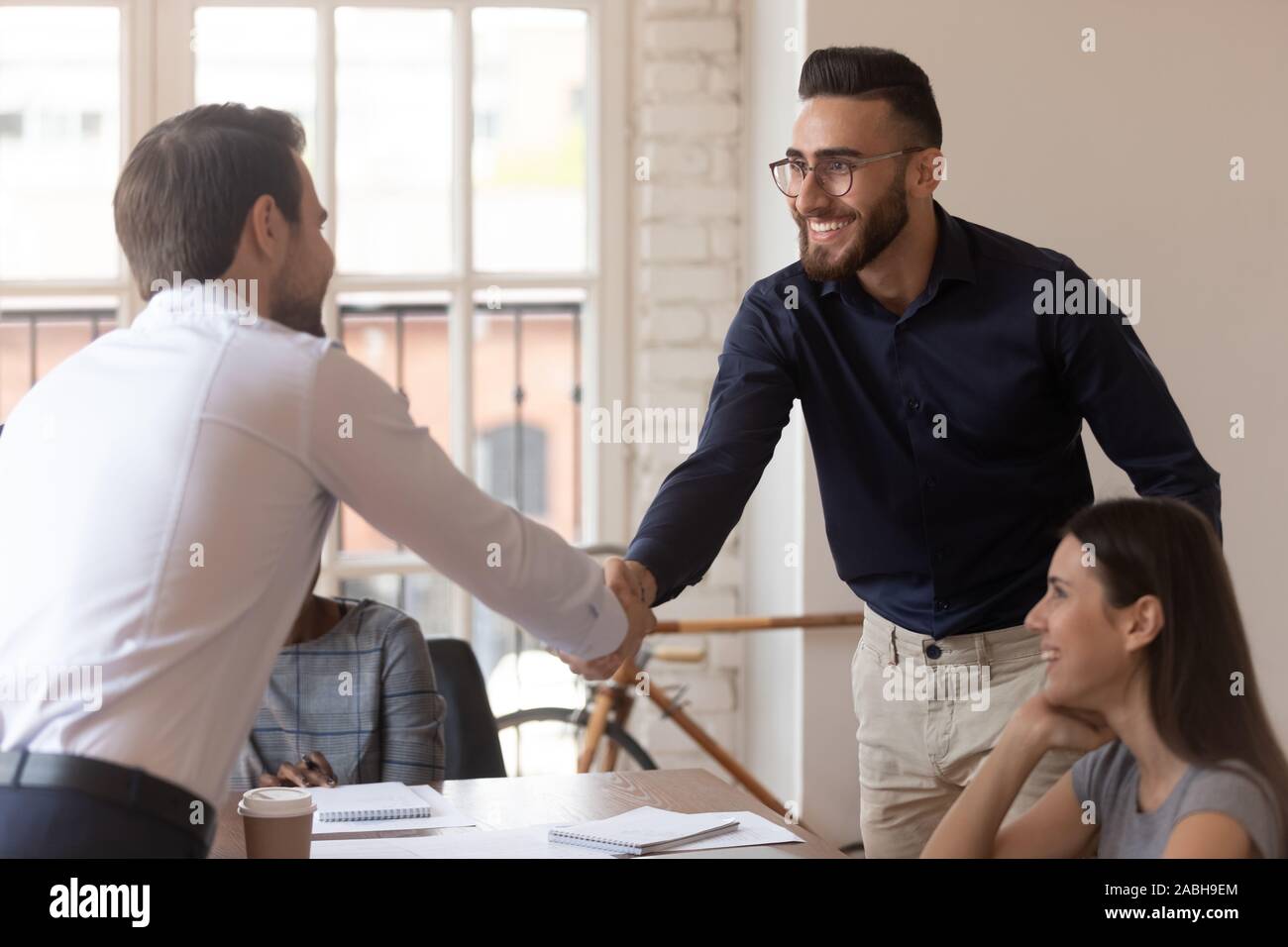 Confident male team leader shaking hands with young arabic employee ...