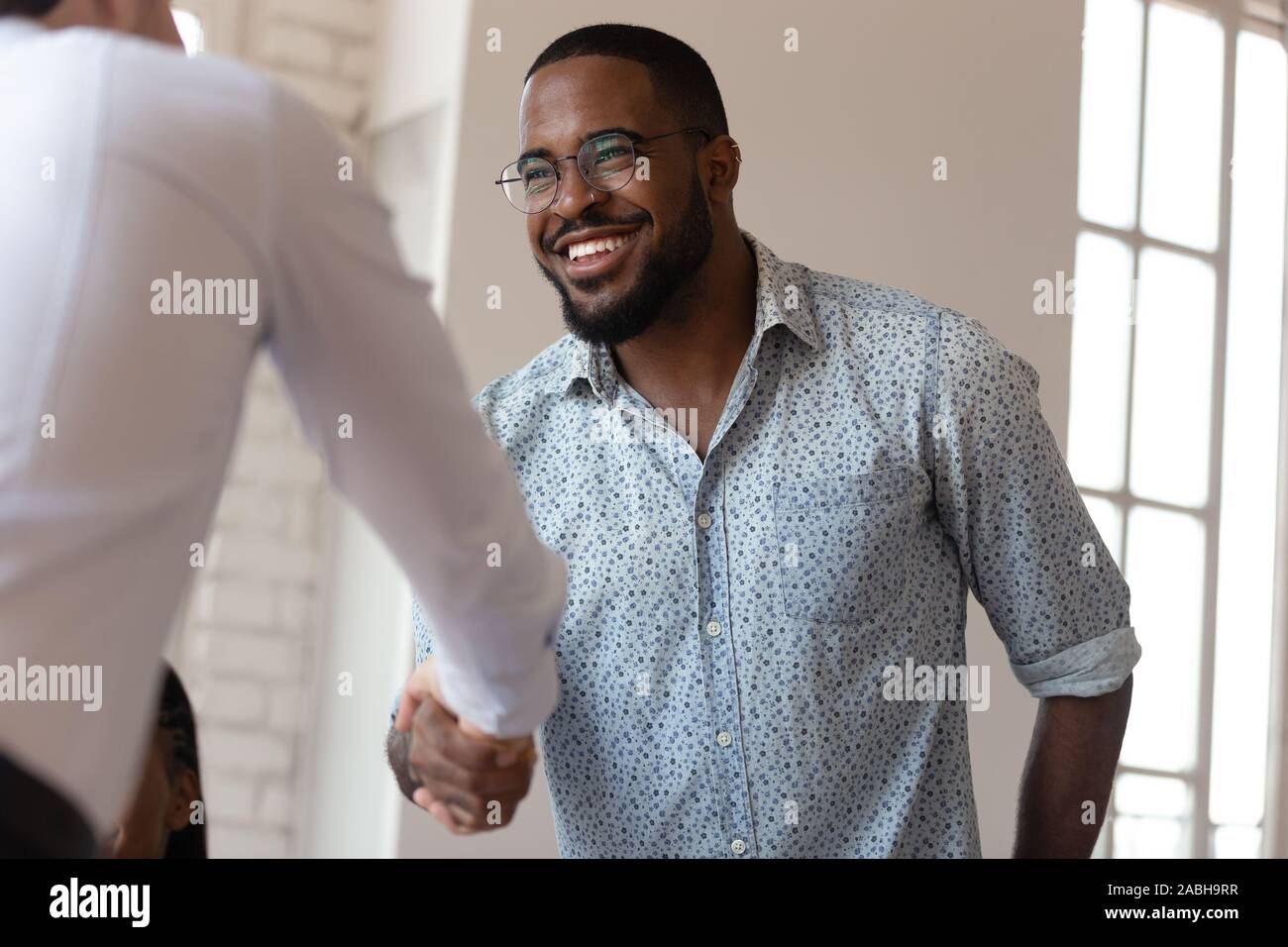Joyful african american millennial worker shaking hands with colleague ...