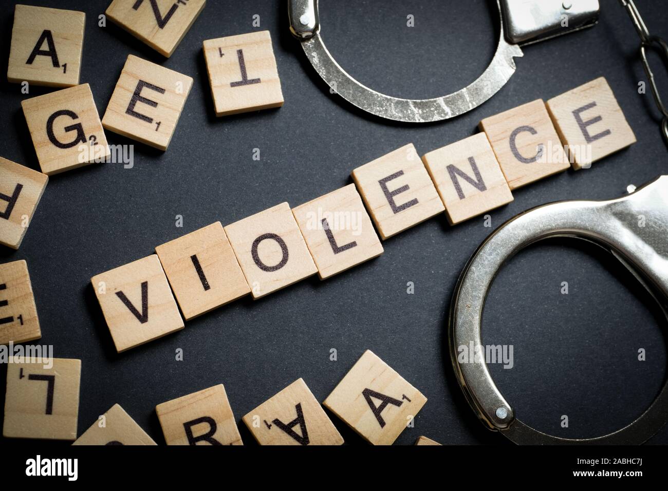 Word made of wooden letters - violence, on black with handcuffs. Crime ...