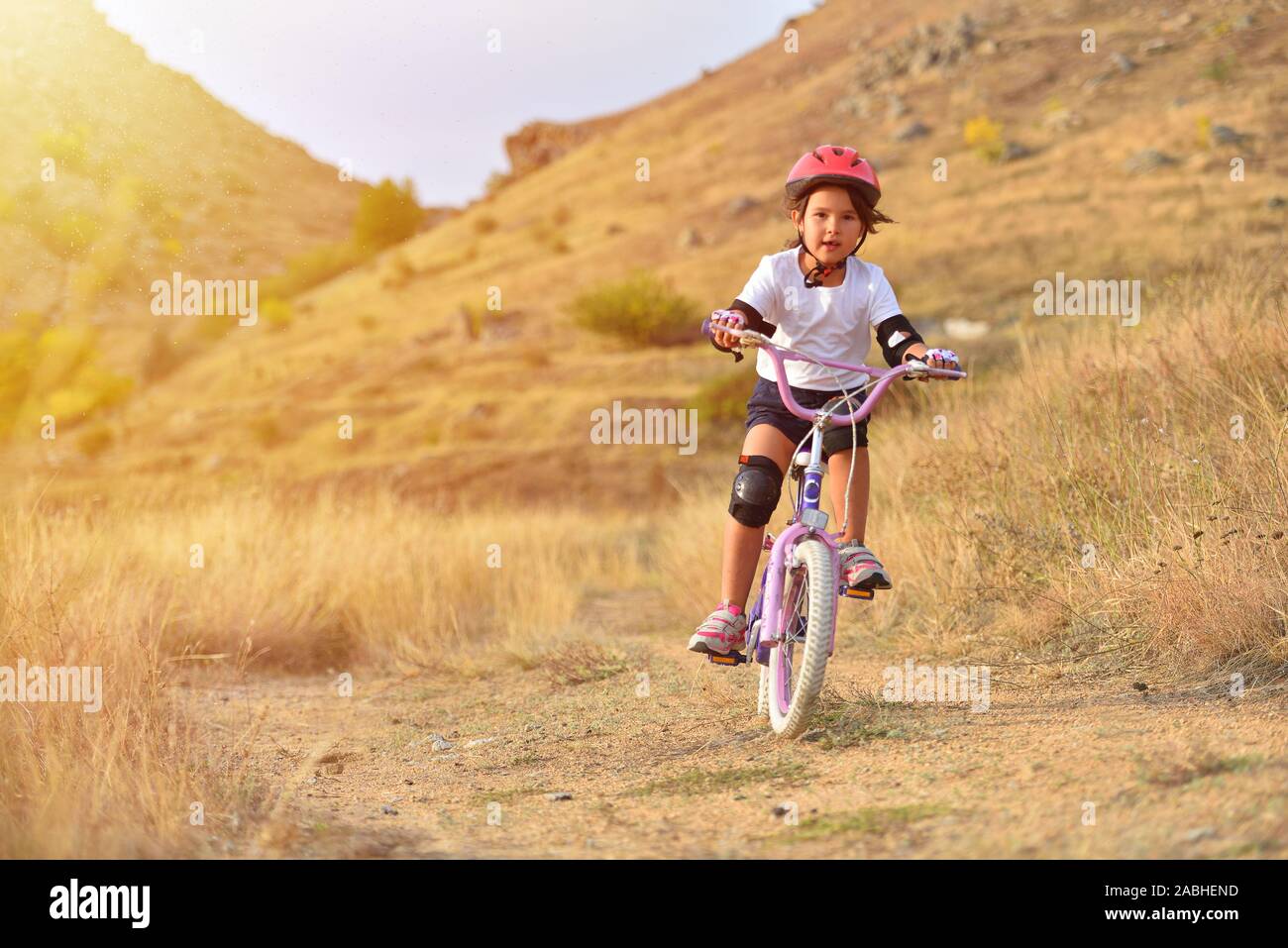 Happy kid girl of 7 years having fun in autumn park with a bicycle on ...
