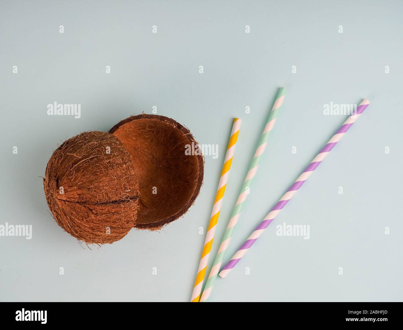 coconut with a drinking tube on a light blue background, close-up ...