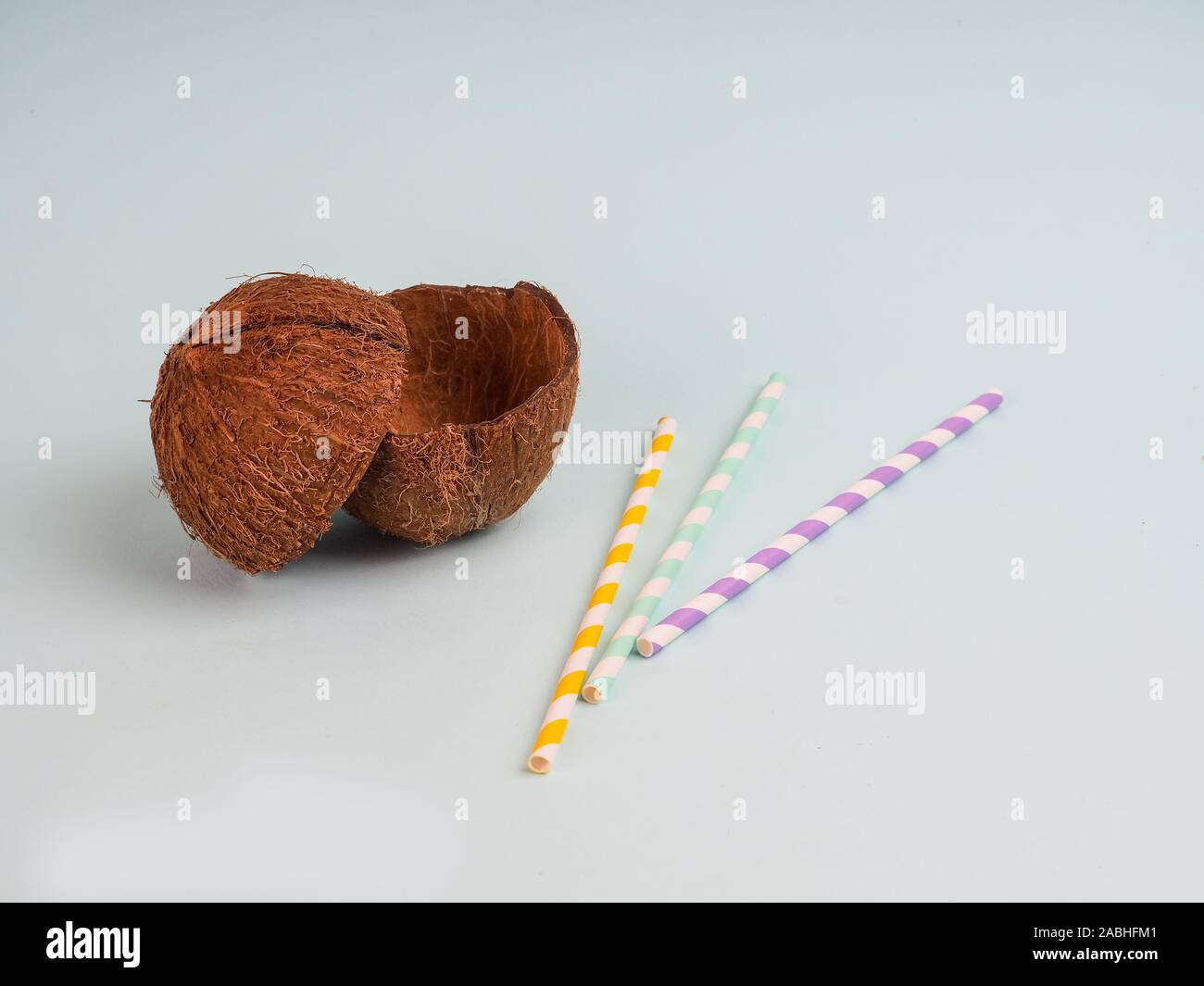 coconut with a drinking tube on a light blue background, close-up ...