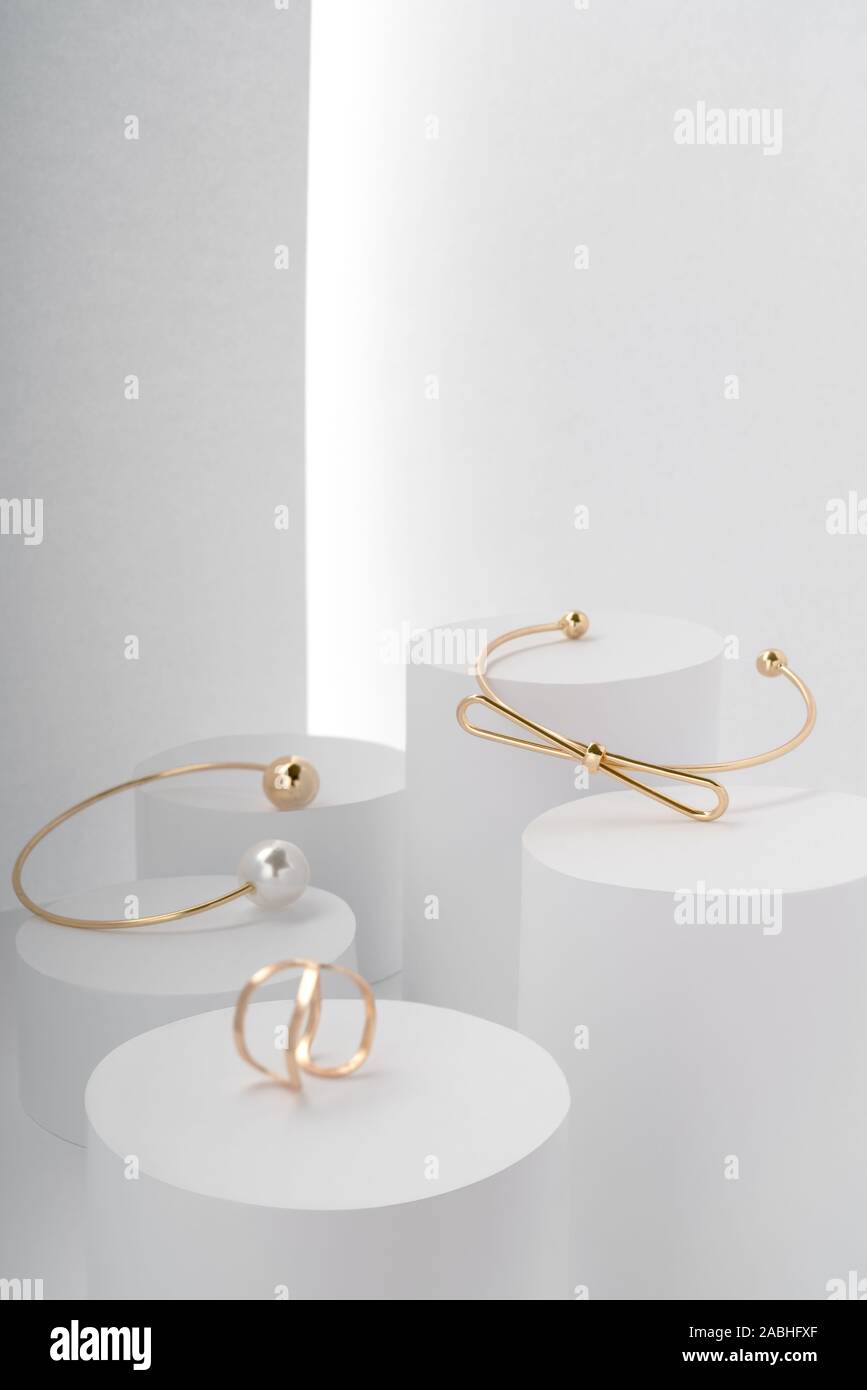 Modern golden bracelets and golden ring on white round platform Stock ...