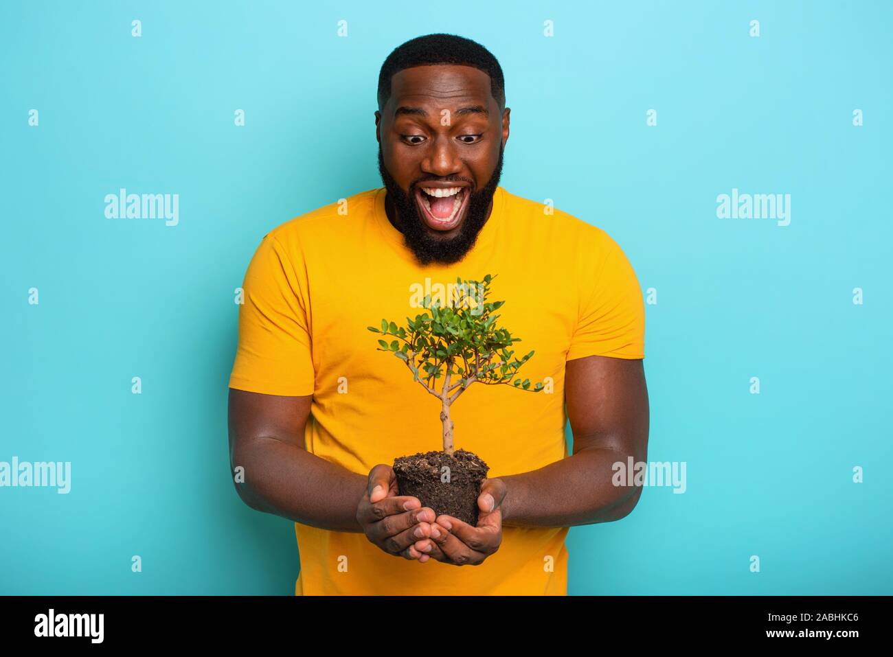 Happy surprised boy hold a small tree ready to be planted. Concept of ...