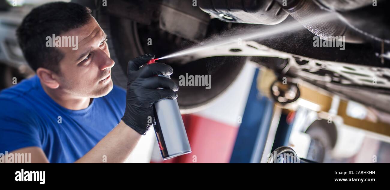 Car master mechanic repairer lubricates the screws with a machine parts ...