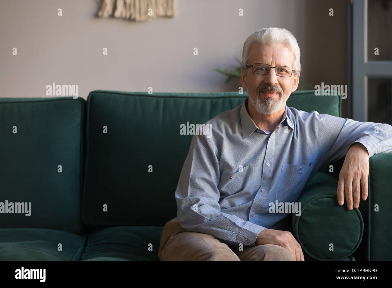 Single handsome elderly man sitting on couch looking at camera Stock ...