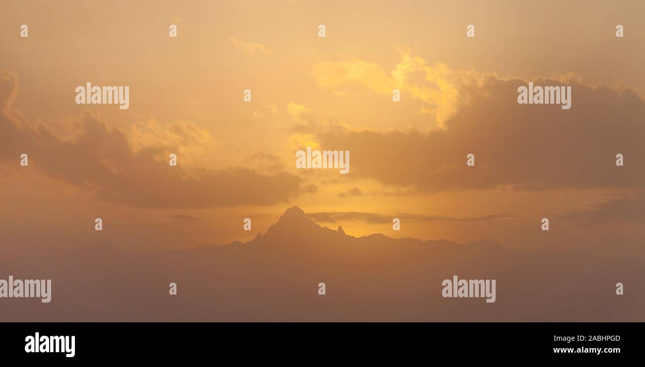 view of Mount Kenya, at sunrise from a distance with clouds above, wide ...