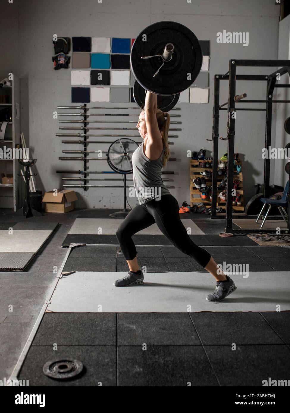 Young female weight lifter struggles with putting a heavy barbell over ...