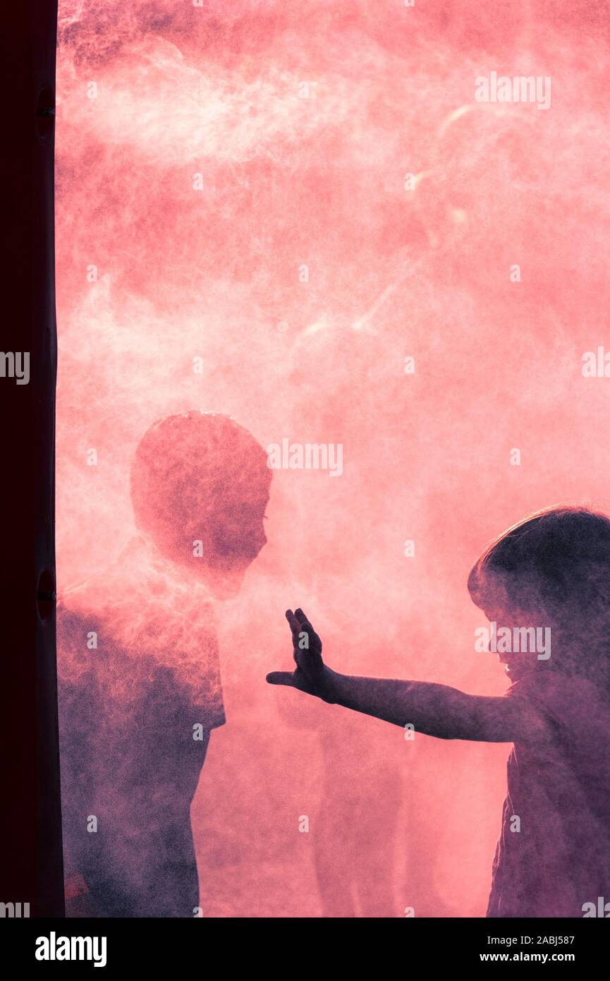 Children playing through a misting machine on a hot summer day during ...