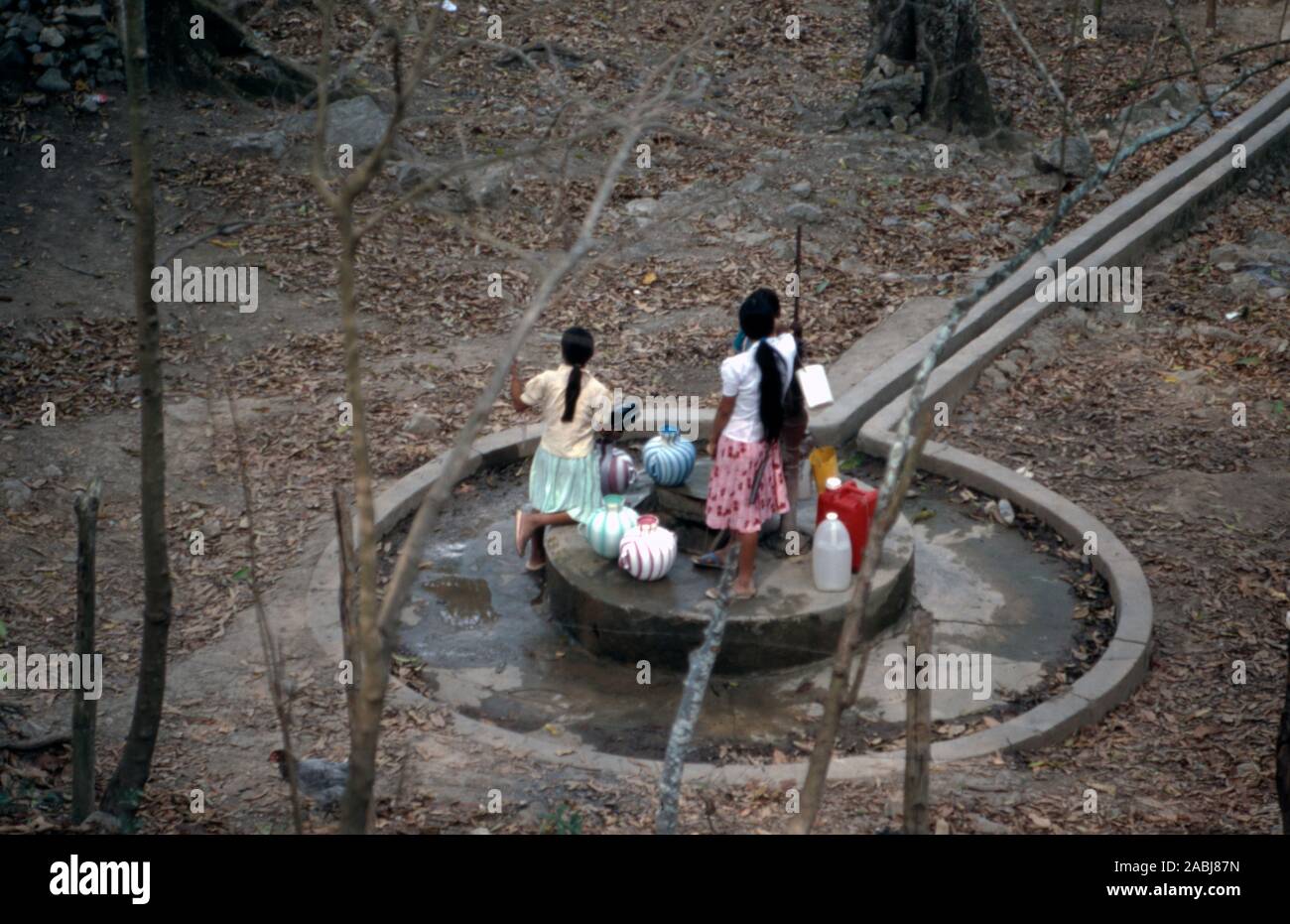 Two young, indigenous Maya girls drawing water from a well in ...