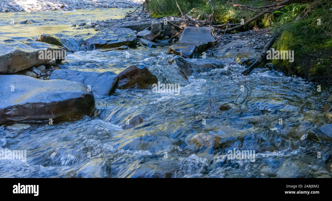 Beautiful flowing mountain stream along a rocky riverbed, lined with ...