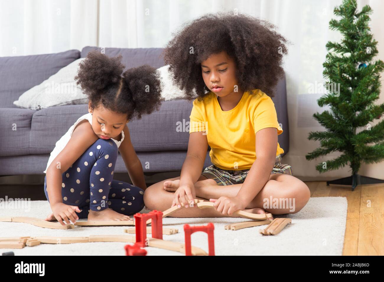 two black girl daughter kids playing train model together at living ...