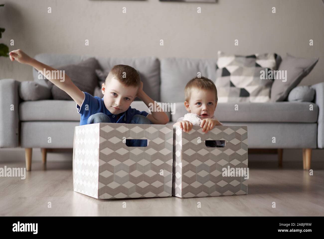 Two boys sitting in cardboard box in room in apartment Stock Photo - Alamy