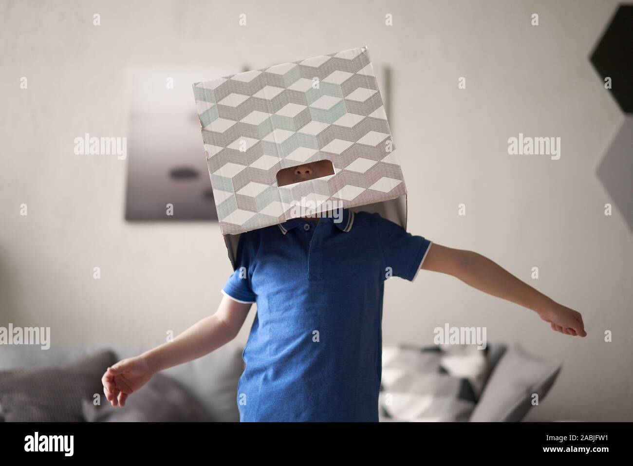 Boy with cardboard box on head in room in apartment Stock Photo - Alamy