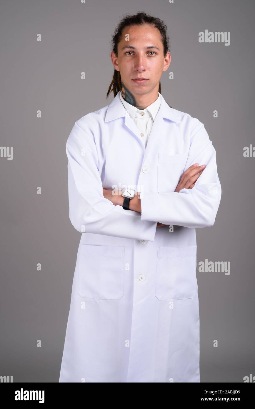 Young man doctor with dreadlocks against gray background Stock Photo ...