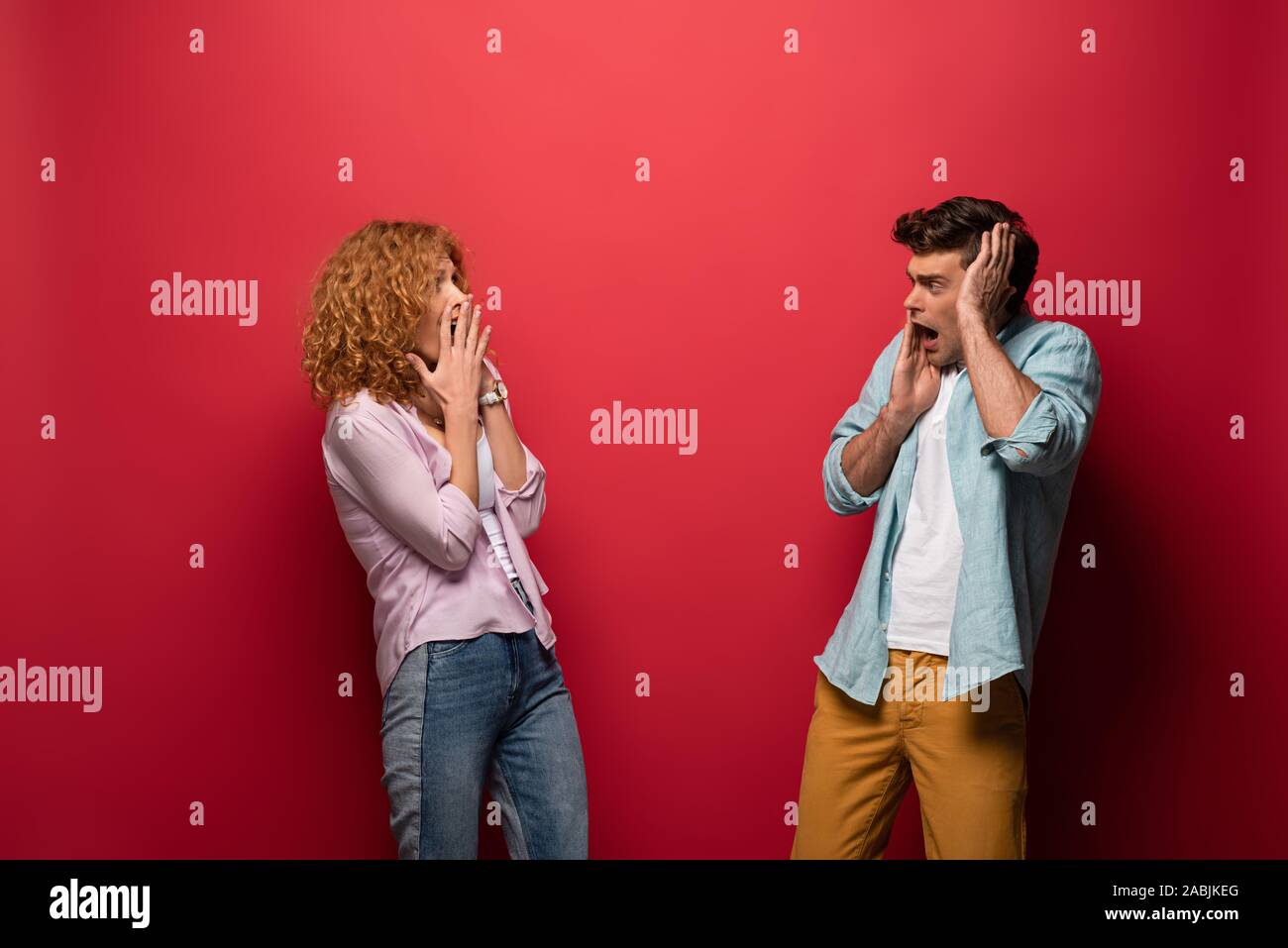beautiful scared couple looking at each other, isolated on red Stock ...