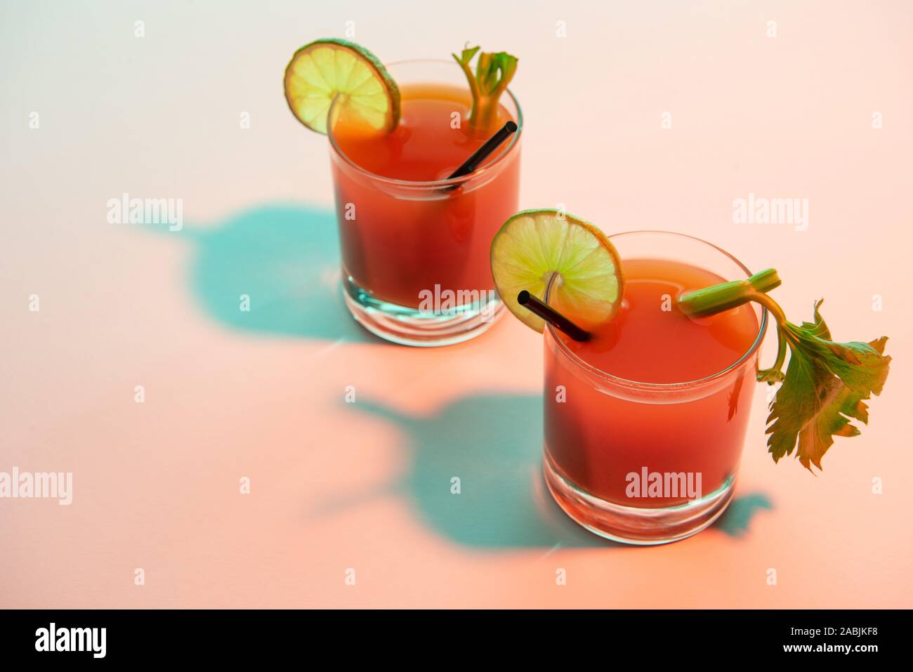 bloody mary cocktail in glasses garnished with lime and celery on red ...