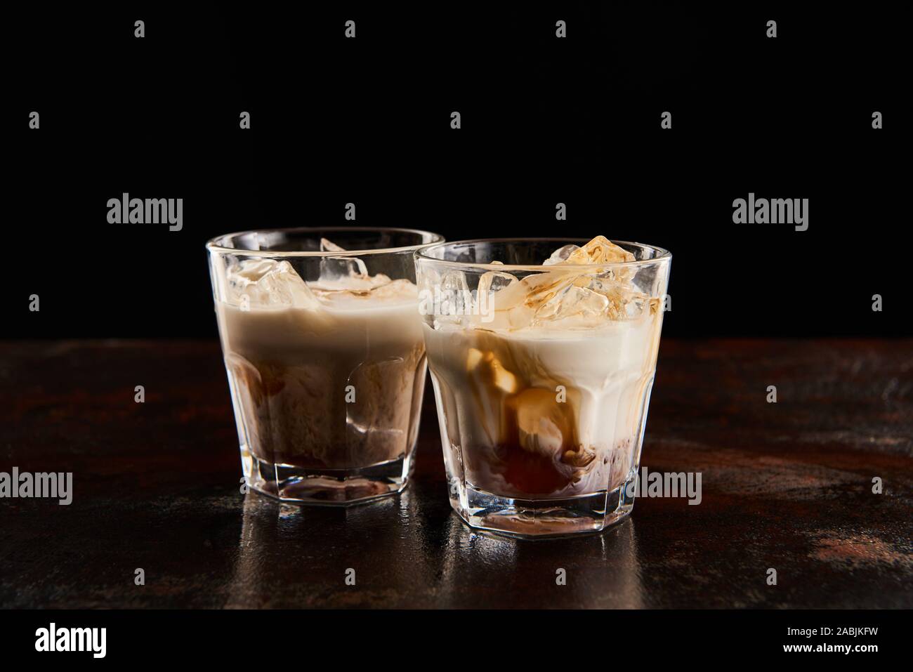 white russian cocktail in glasses with ice cubes isolated on black ...