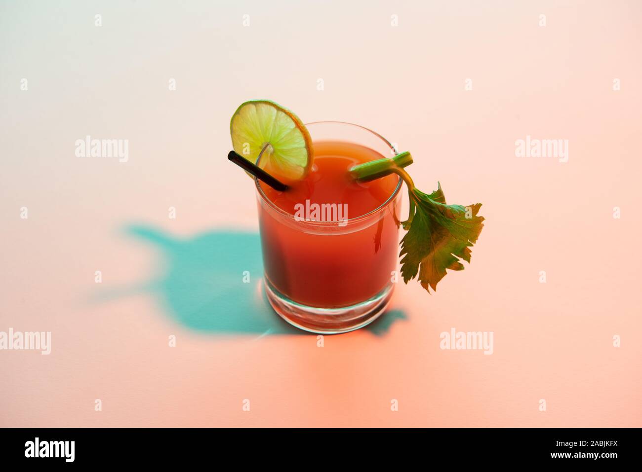 bloody mary cocktail in glass garnished with lime and celery on red and ...
