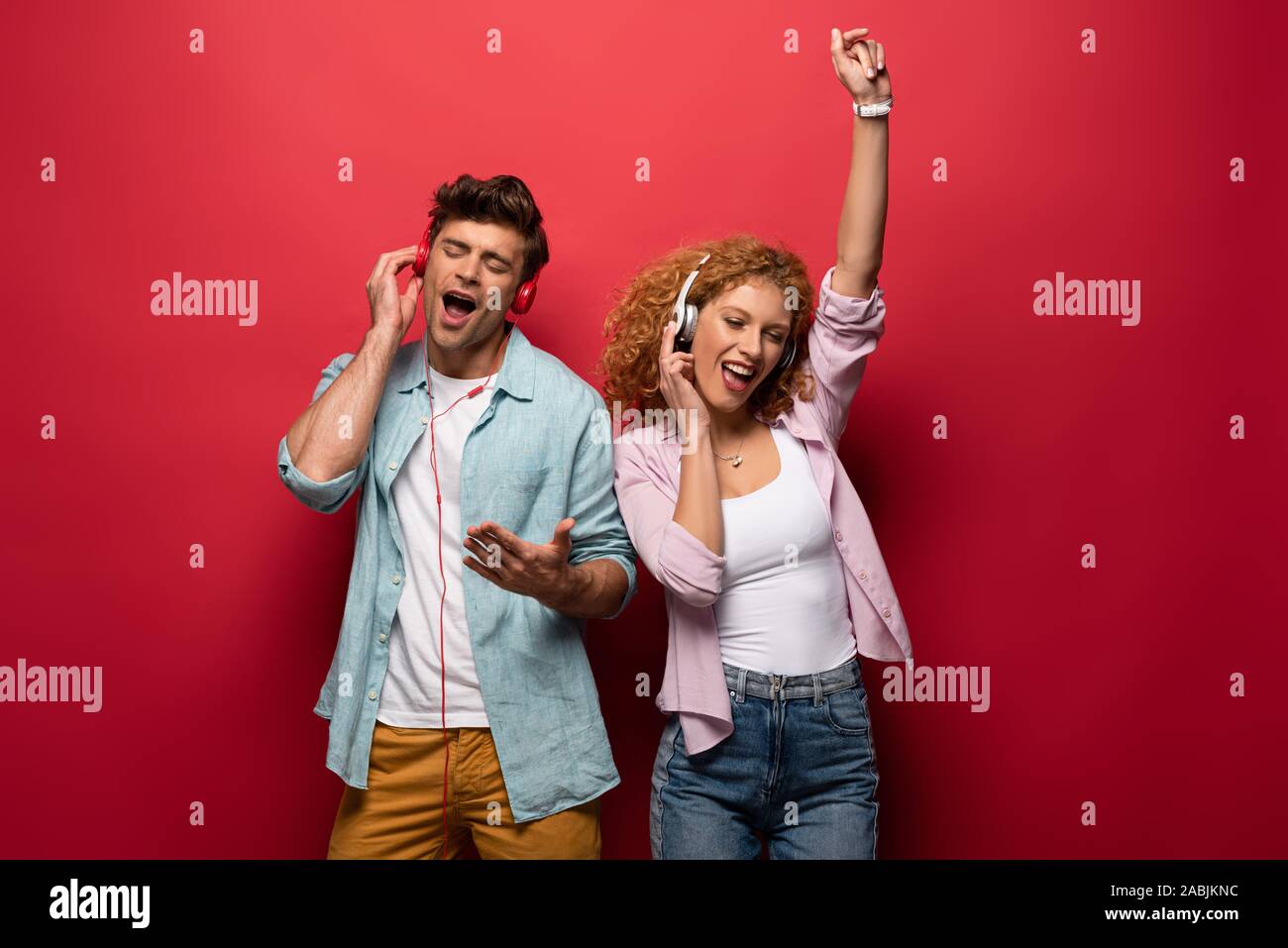 happy couple dancing, singing and listening music with headphones ...