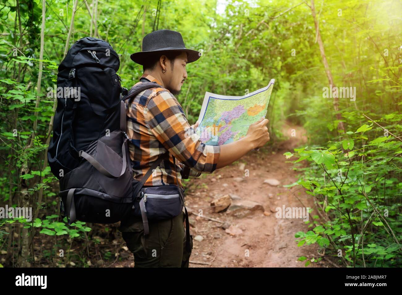 man traveler with backpack and map searching directions in the natural ...