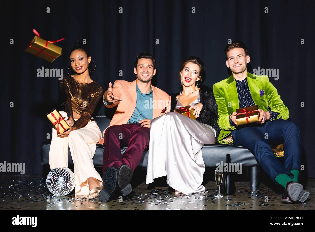 happy man throwing in air present while sitting with multicultural ...