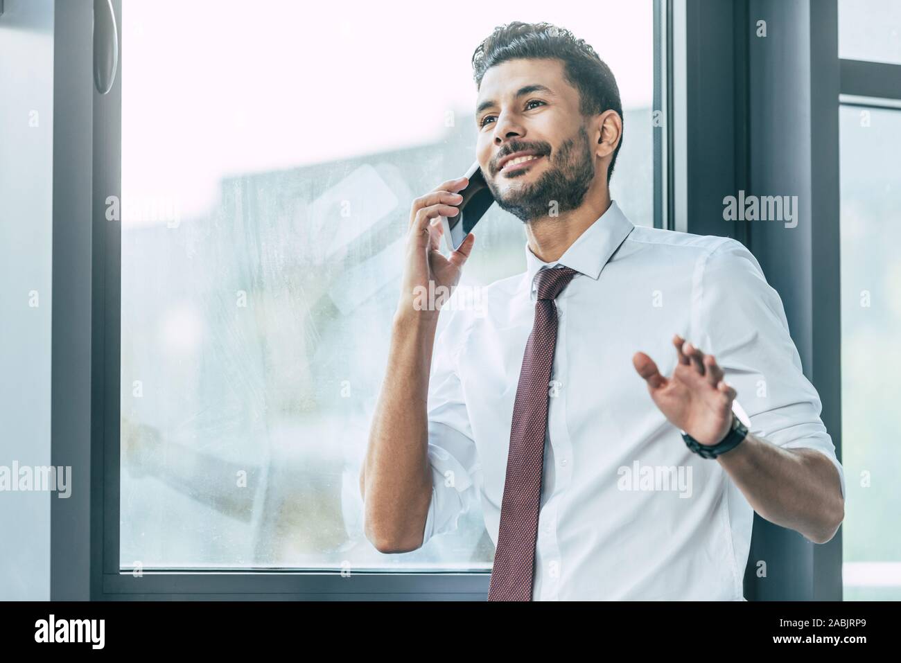 smiling businessman showing wait gesture while talking on smartphone ...