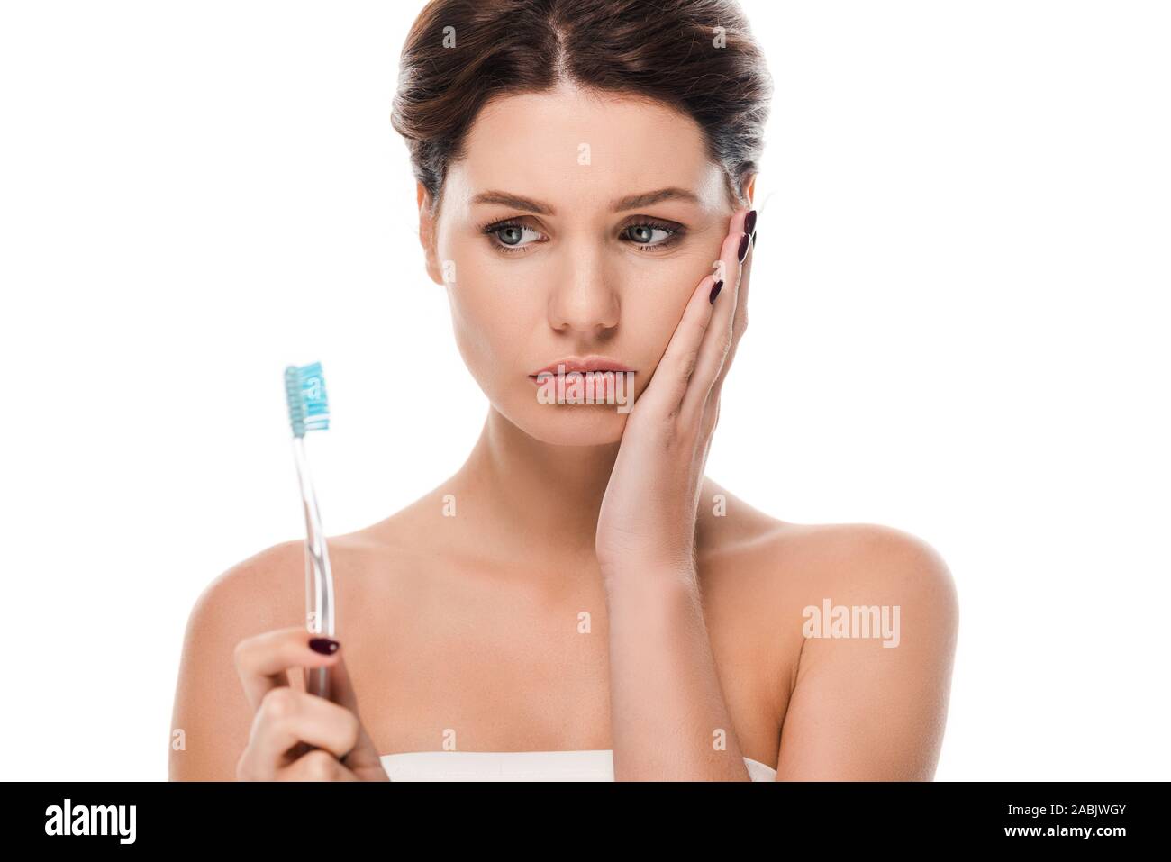 sad young woman touching face while holding toothbrush isolated on ...