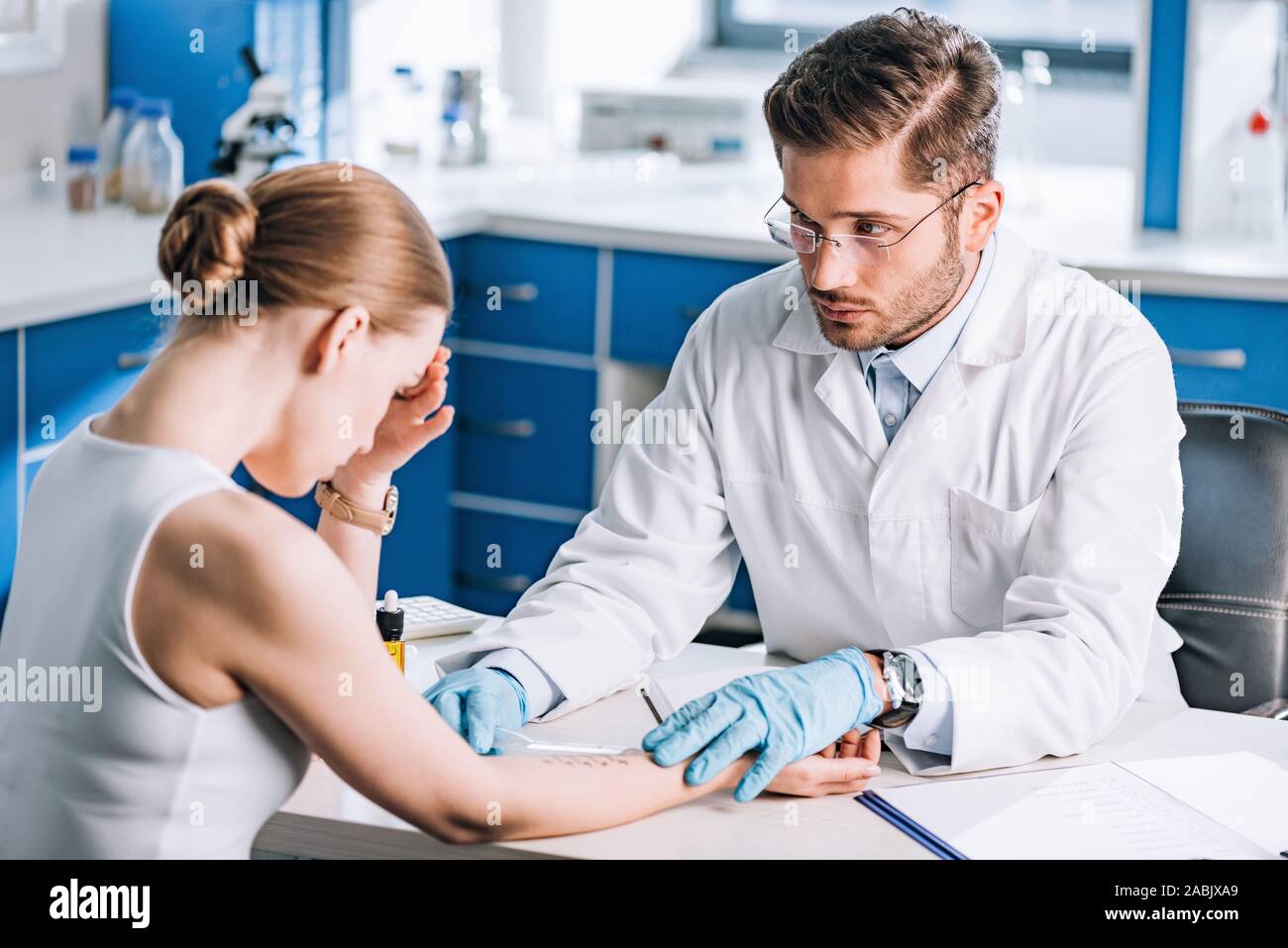 selective focus of handsome allergist holding ruler near marked hand of ...