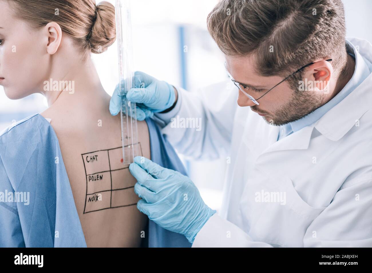 bearded allergist holding ruler near patient with marked back Stock ...