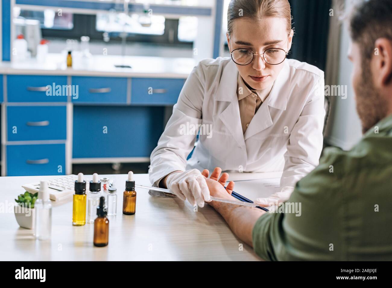 selective focus of attractive allergist holding ruler near hand on man ...