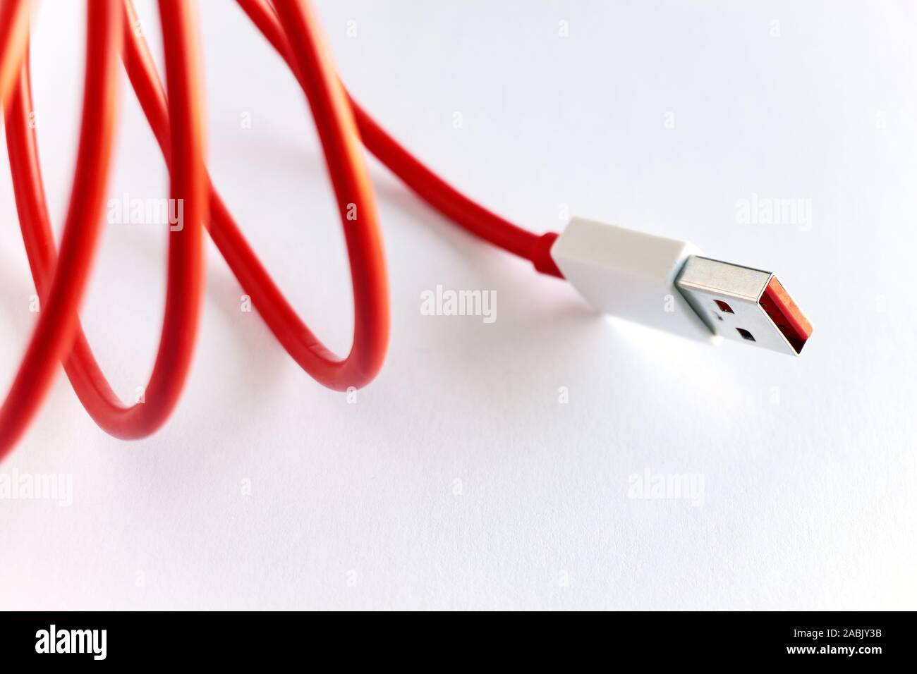 Close-up of red curled USB cable isolated on white background with copy ...