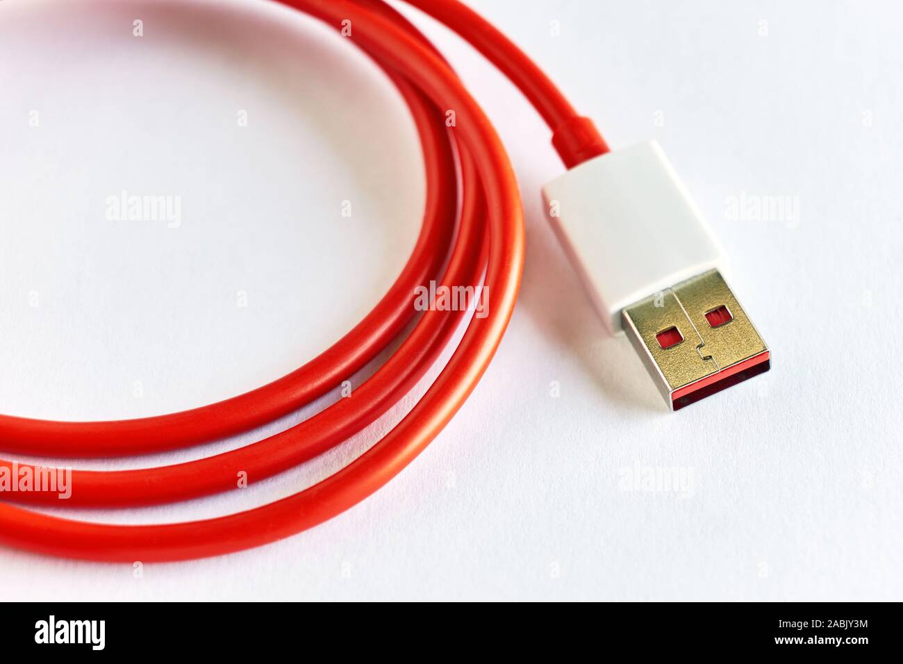Close-up of red curled USB cable on white background with copy space ...