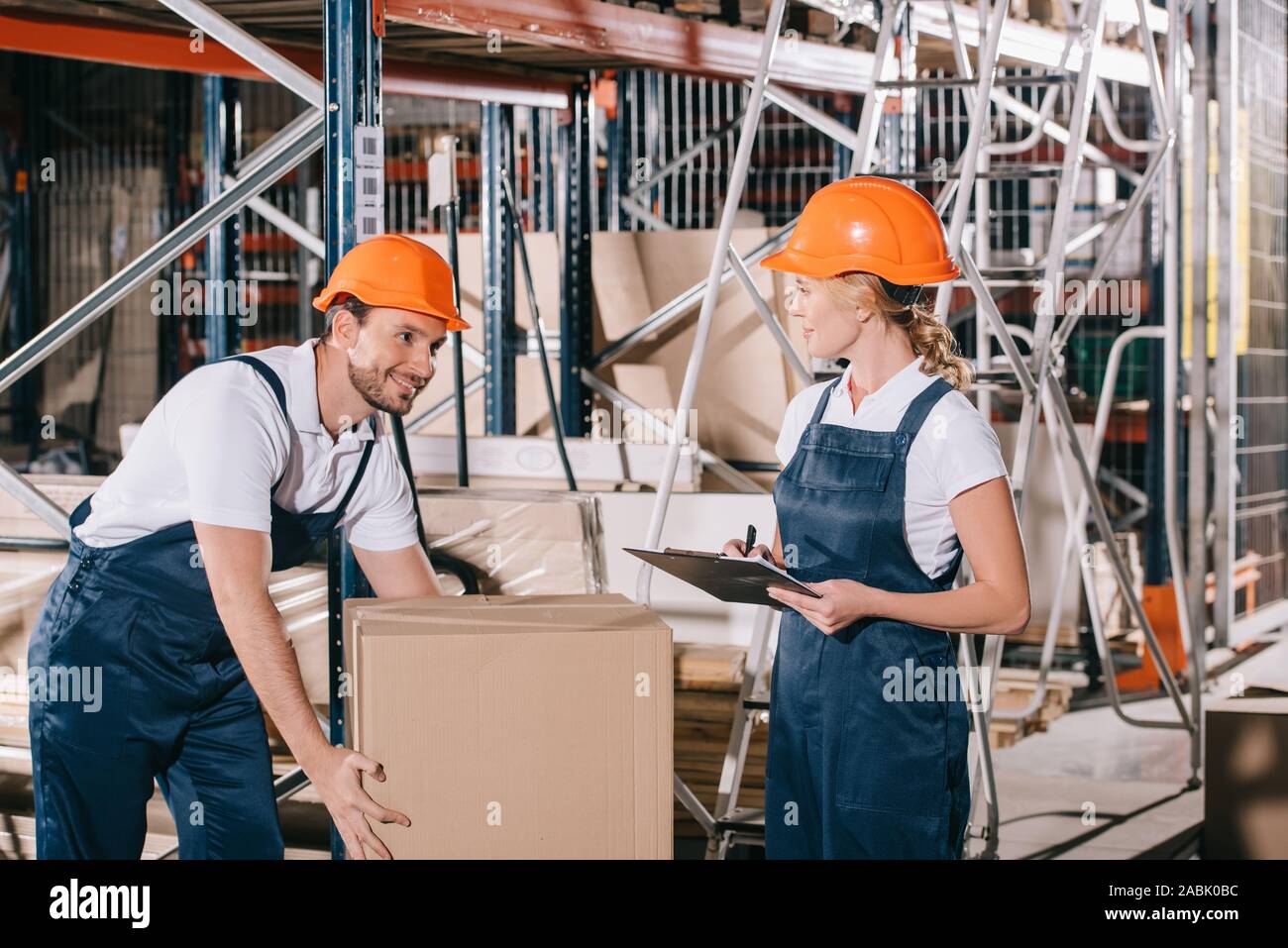 smiling loader holding cardboard box and looking at workwoman with ...