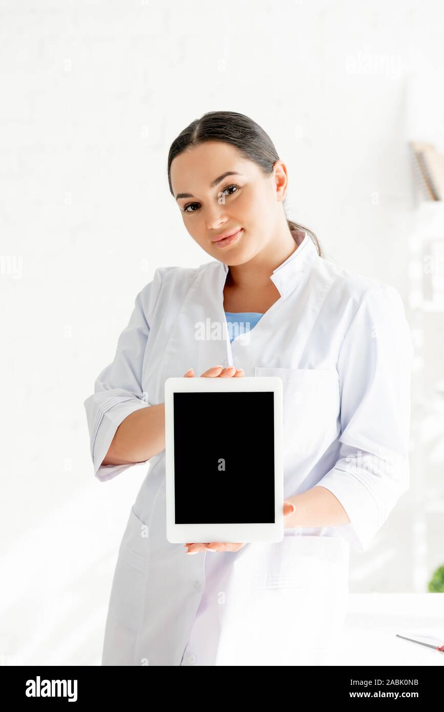 attractive dermatologist holding digital tablet and looking at camera ...