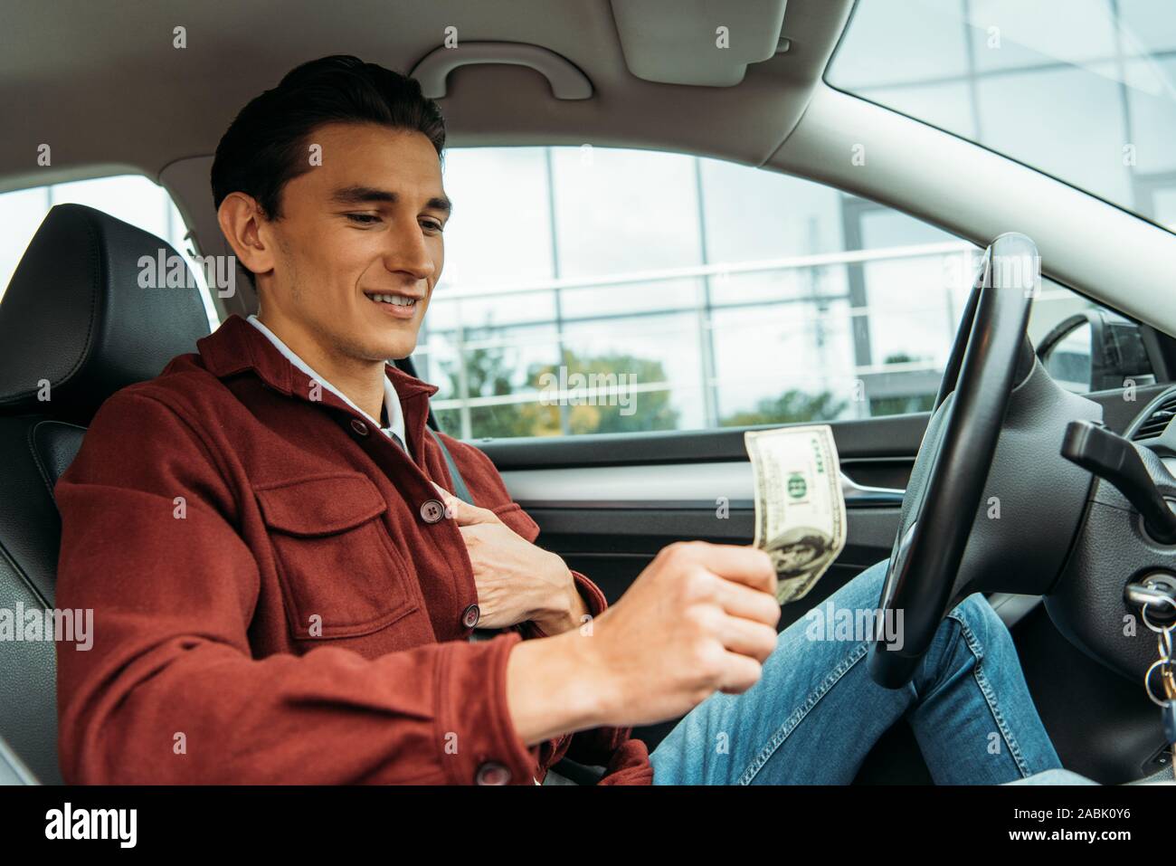 Man taxi driver holding dollar banknote in car Stock Photo - Alamy