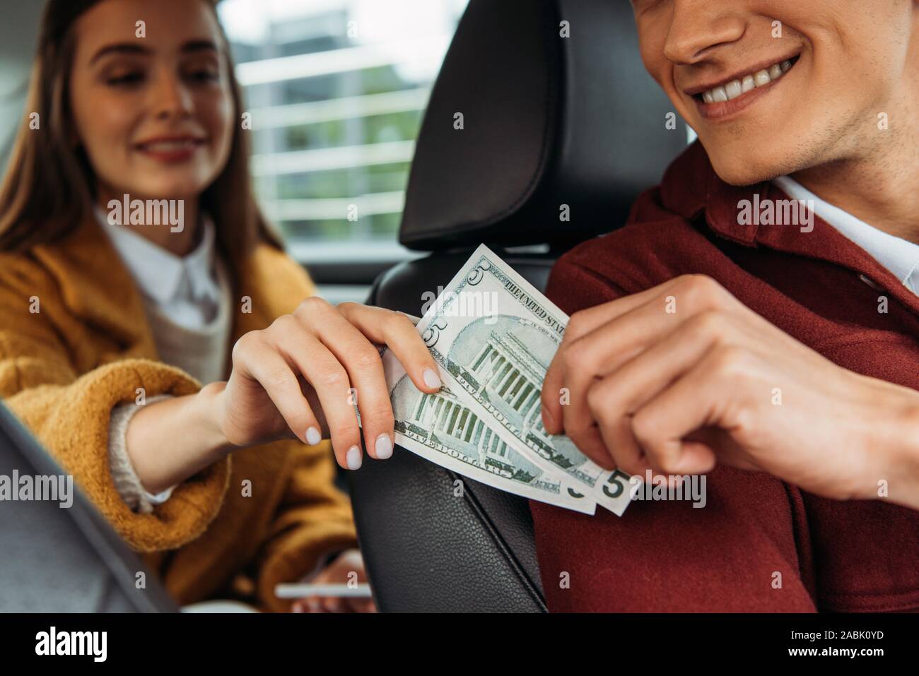 Selective focus of passenger giving dollar banknotes to taxi driver ...
