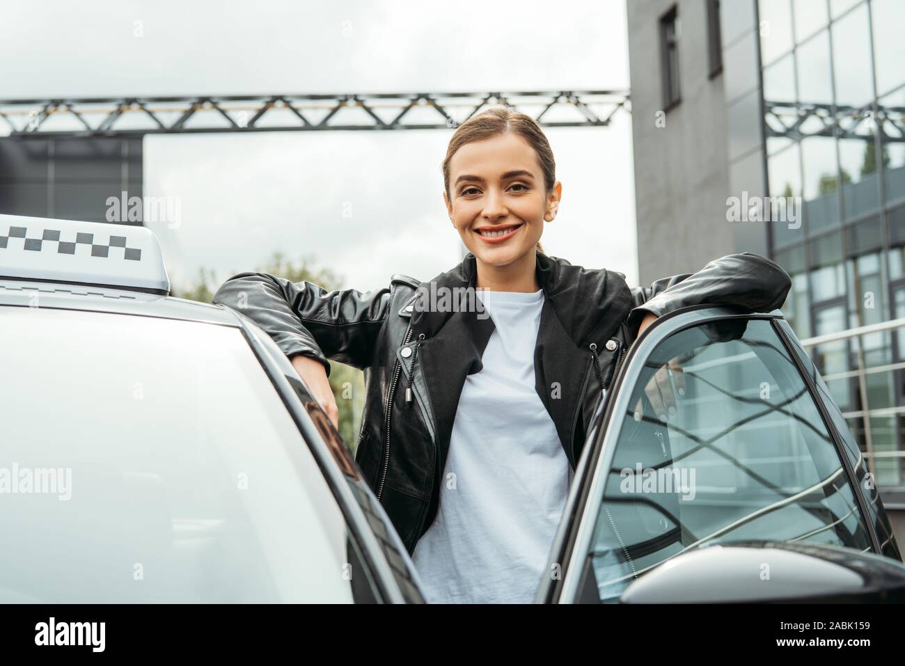 Woman taxi driver smiling at camera beside car Stock Photo - Alamy