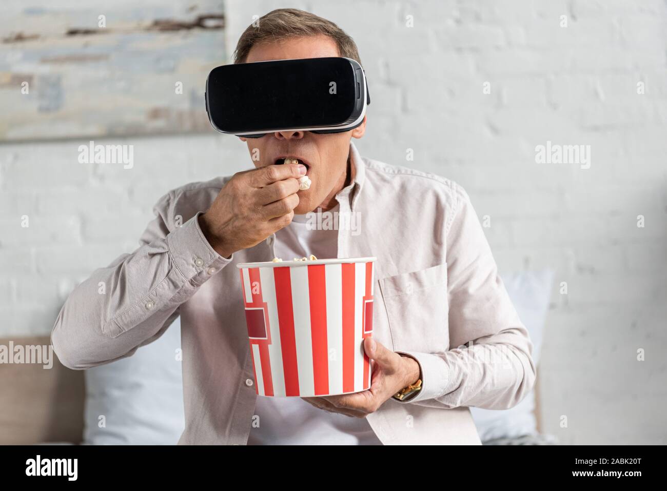 Man in virtual reality headset eating popcorn on bed Stock Photo - Alamy