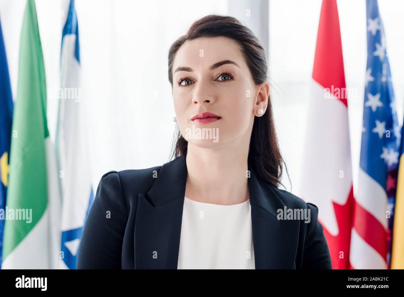 attractive diplomat looking at camera near flags Stock Photo - Alamy