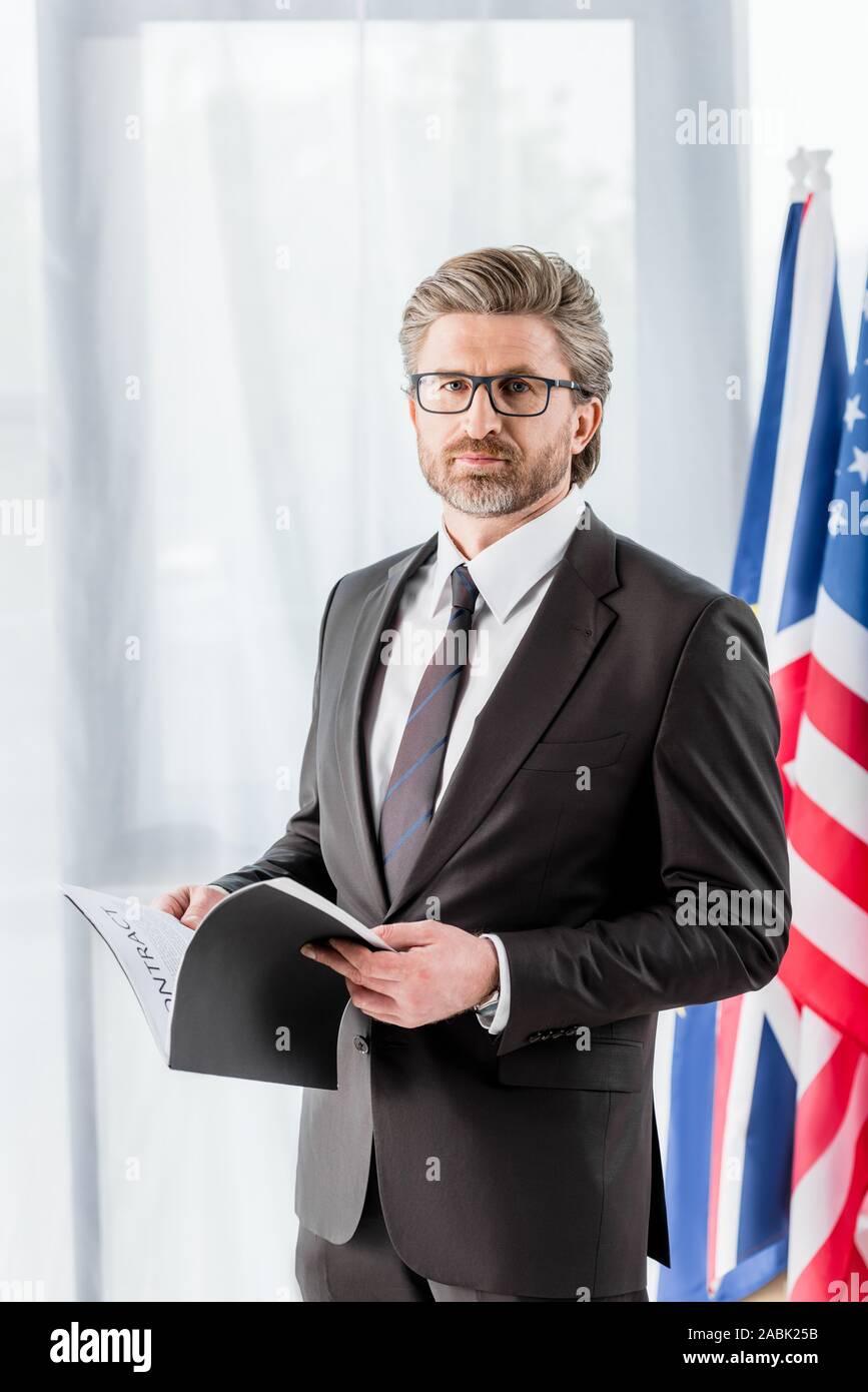 handsome diplomat in glasses holding folder near american flag Stock ...