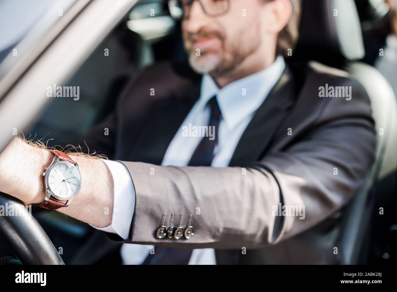 selective focus of luxury watch on hand of ambassador driving car Stock ...