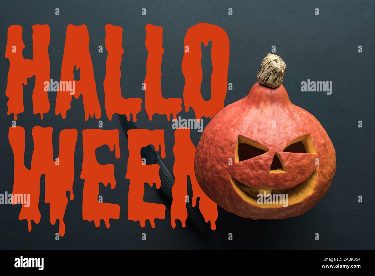 top view of carved spooky Halloween pumpkin with knife on black ...