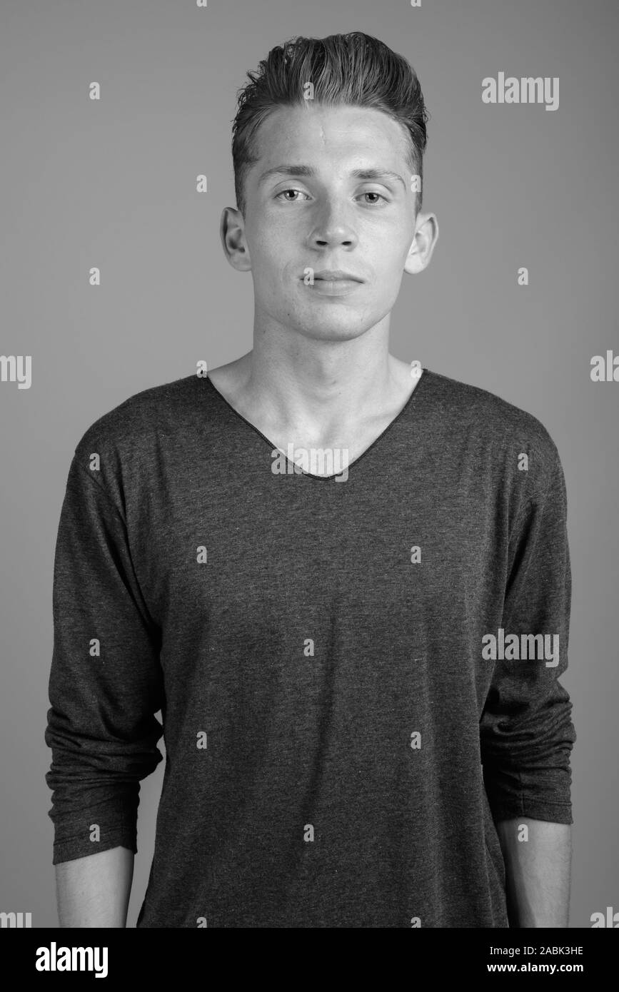 Portrait of young man against gray background in black and white Stock ...