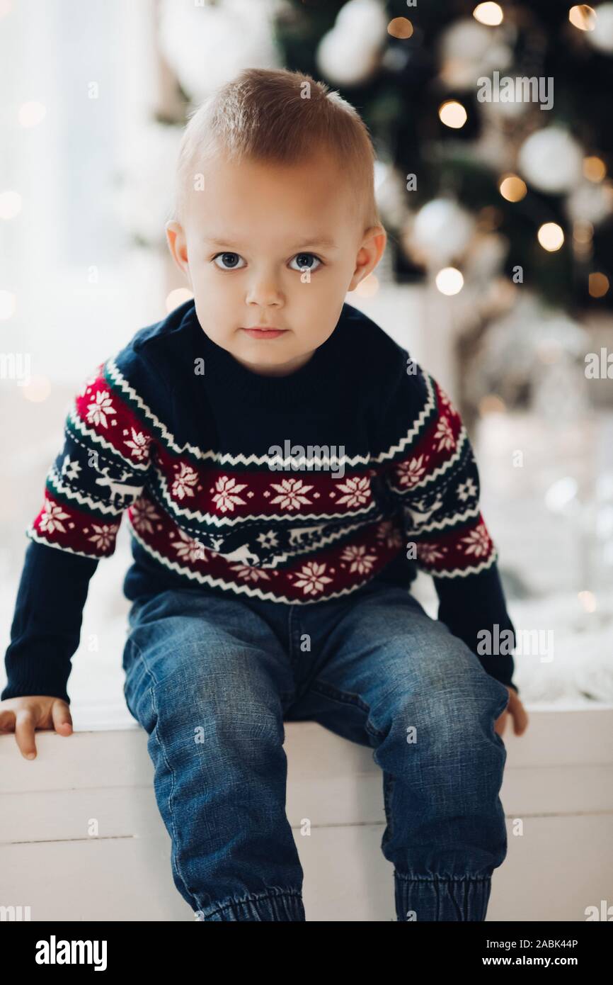 Cute boy in sweater with wrapped red Christmas present Stock Photo - Alamy
